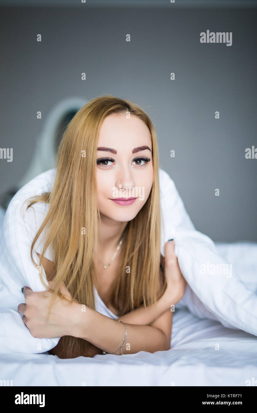 Blonde woman lying under a duvet in a bedroom Stock Photo - Alamy