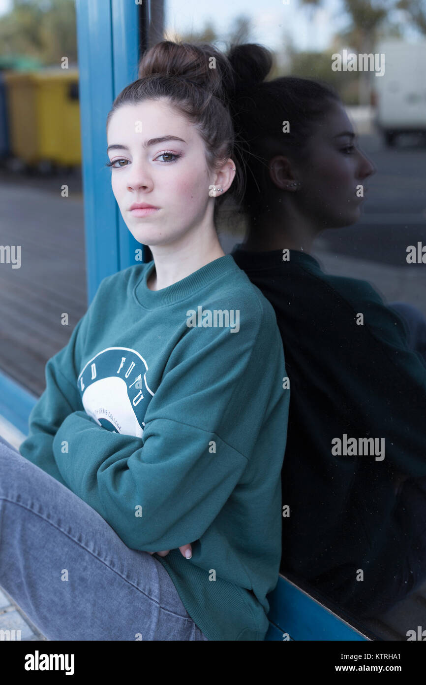Teen girl sitting looking towards the camera. Vertical shot with ...