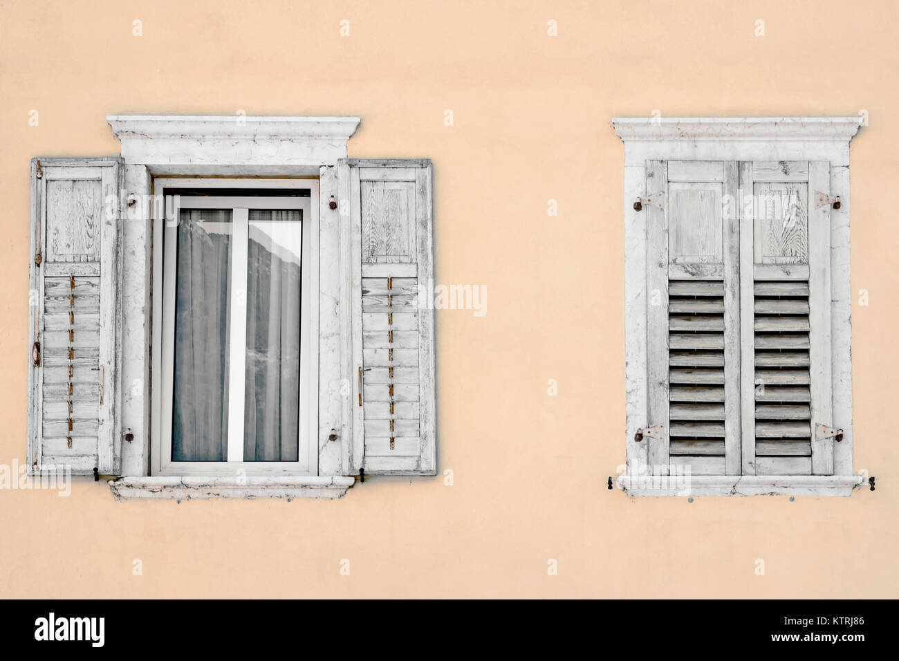 Two windows with window shutters in a beige house Stock Photo - Alamy