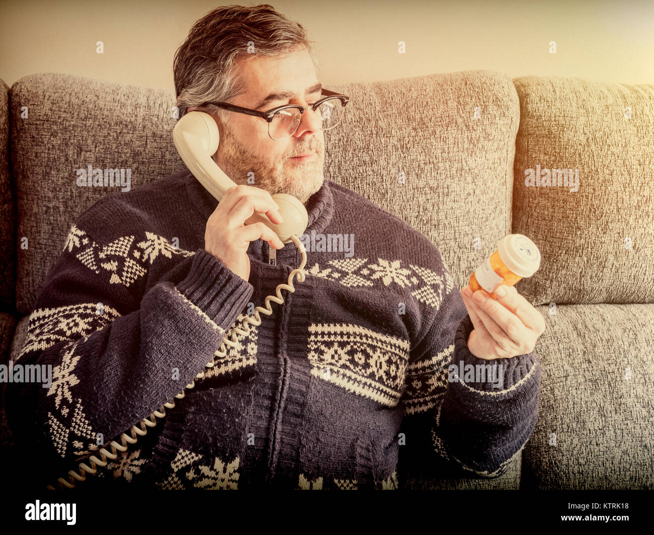 Middle-aged man calling by telephone to hospital with pill bottle in ...