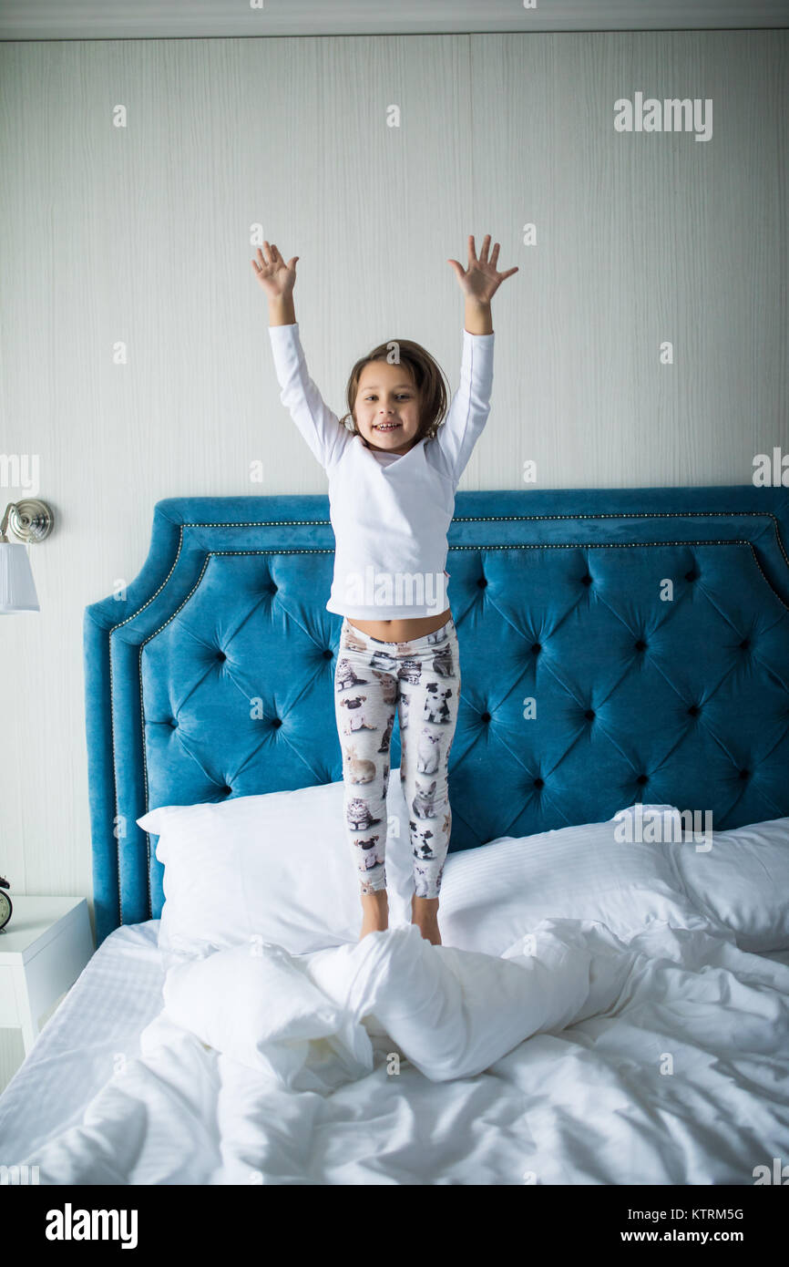 Cute little girl jumping on white bed Stock Photo - Alamy