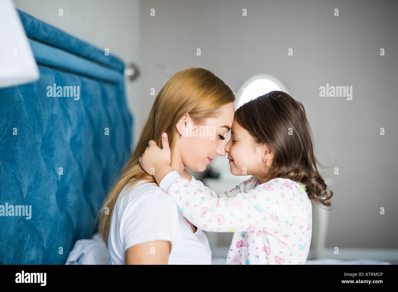 Beautiful young woman and her charming little daughter are hugging and ...