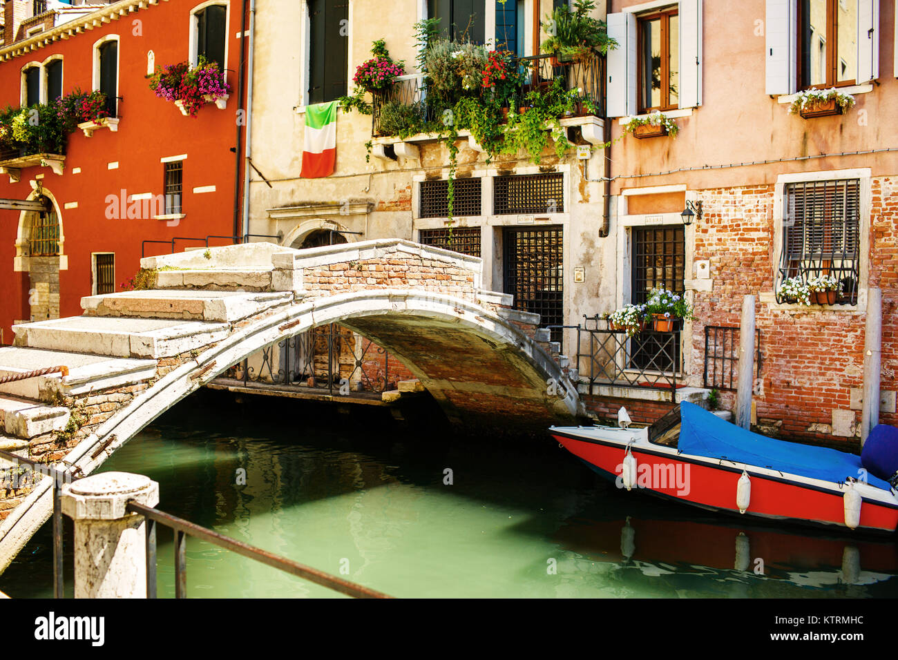 The moored boat next to the colorful house and bridge. Canals in Venice ...