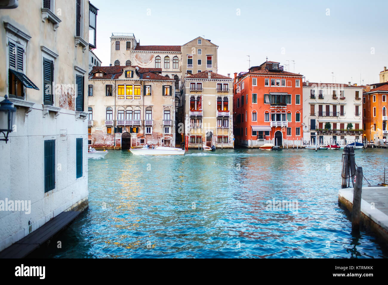 Boats moored between colorful houses and boats floating along the canal ...