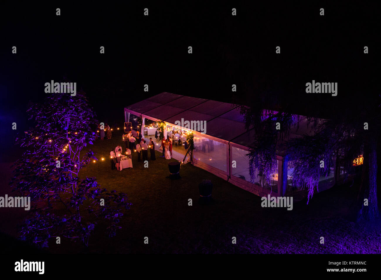 White banquet wedding tent at night with people Stock Photo - Alamy