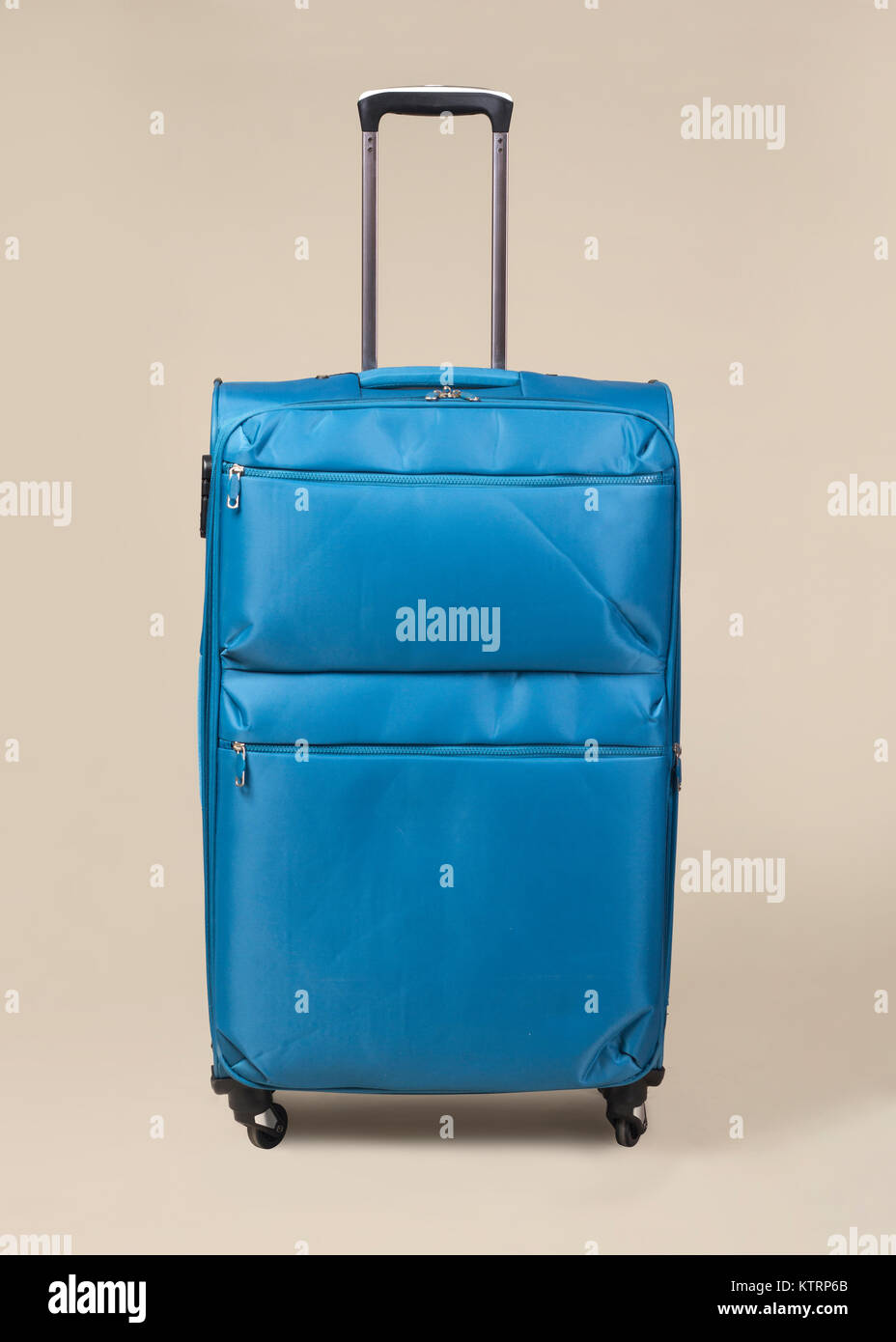 Blue fabric trolley suitcase isolated on beige background Stock Photo ...