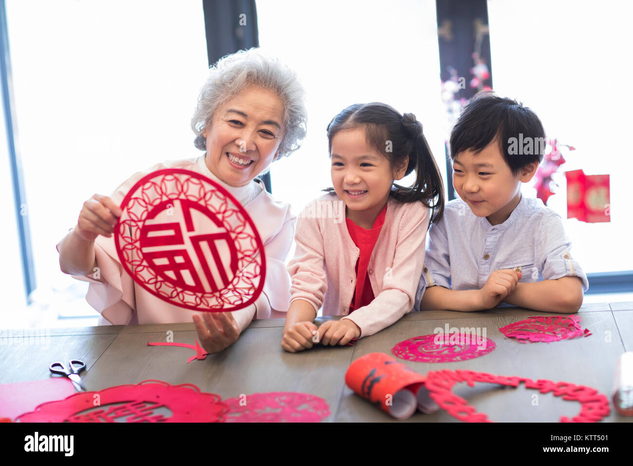 Grandchildren and grandmother with Chinese New Year paper-cut Stock ...