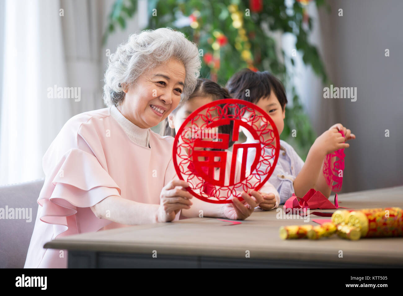Grandchildren and grandmother with Chinese New Year paper-cut Stock ...
