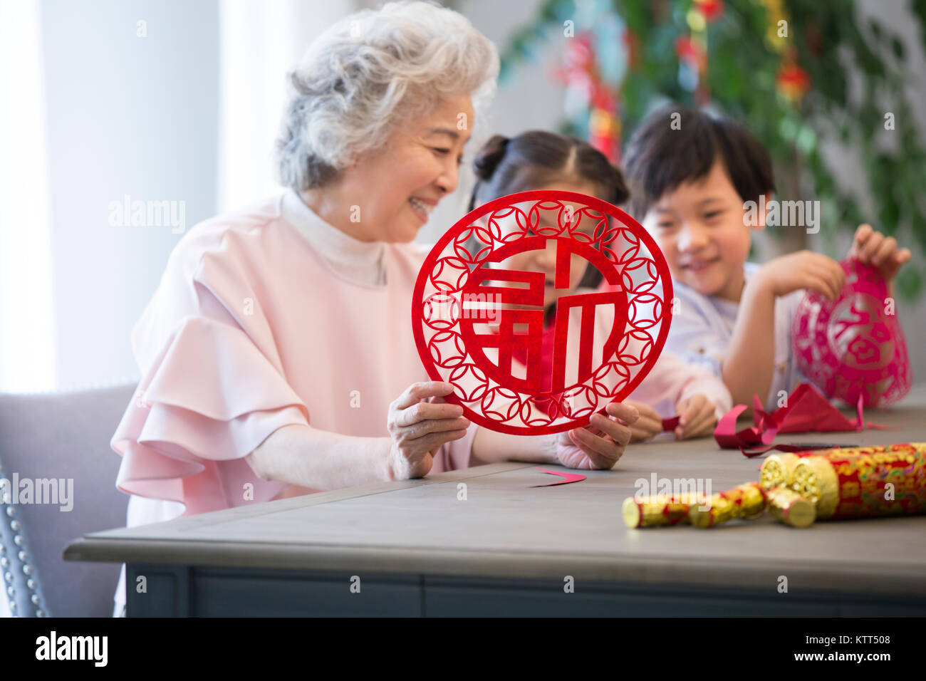 Grandchildren and grandmother with Chinese New Year paper-cut Stock ...