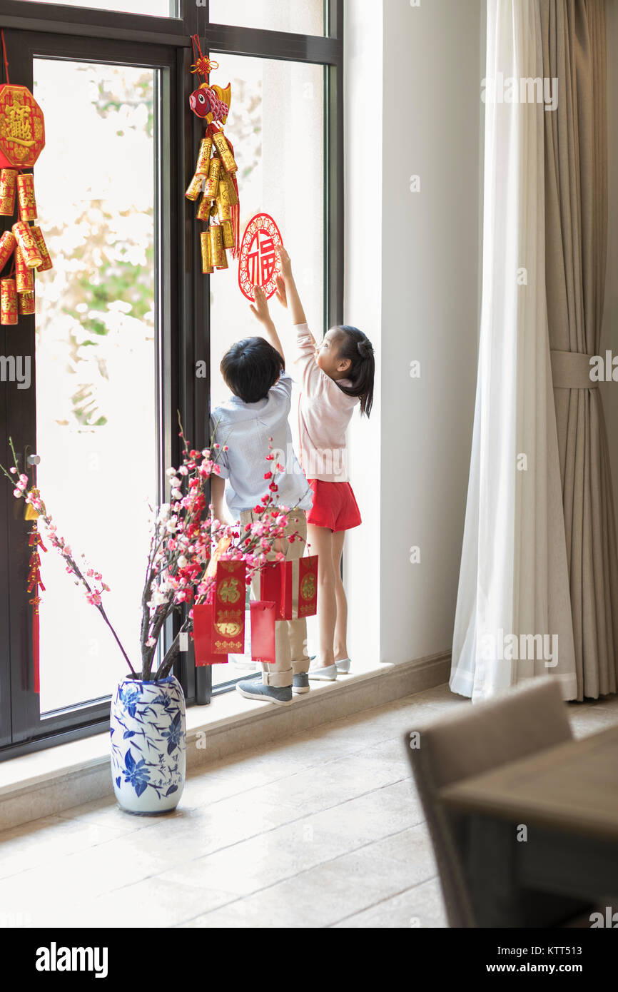 Cheerful children with Chinese New Year paper-cut for window decoration ...