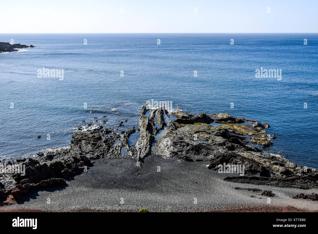 Volcanic rocks protruding from the assessment at the coast of the ...