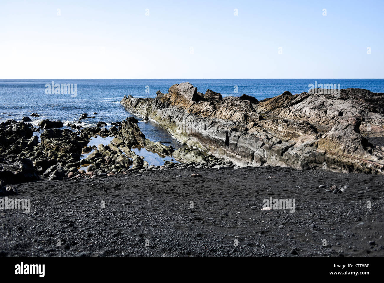Volcanic rocks protruding from the assessment at the coast of the ...
