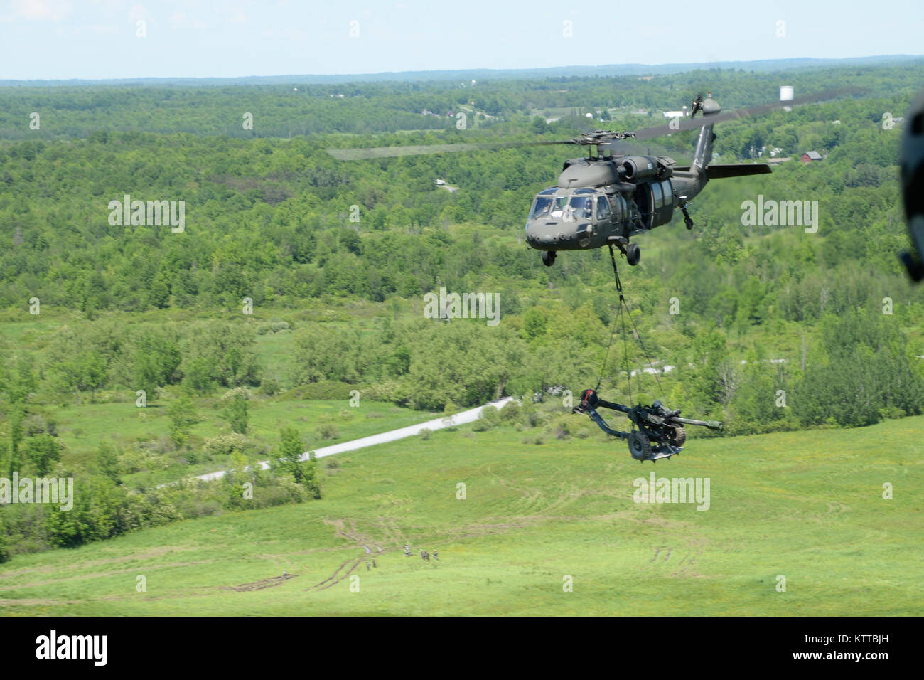 A UH-60 Black Hawk Helicopter transports a M119A2 Howitzer over Fort ...