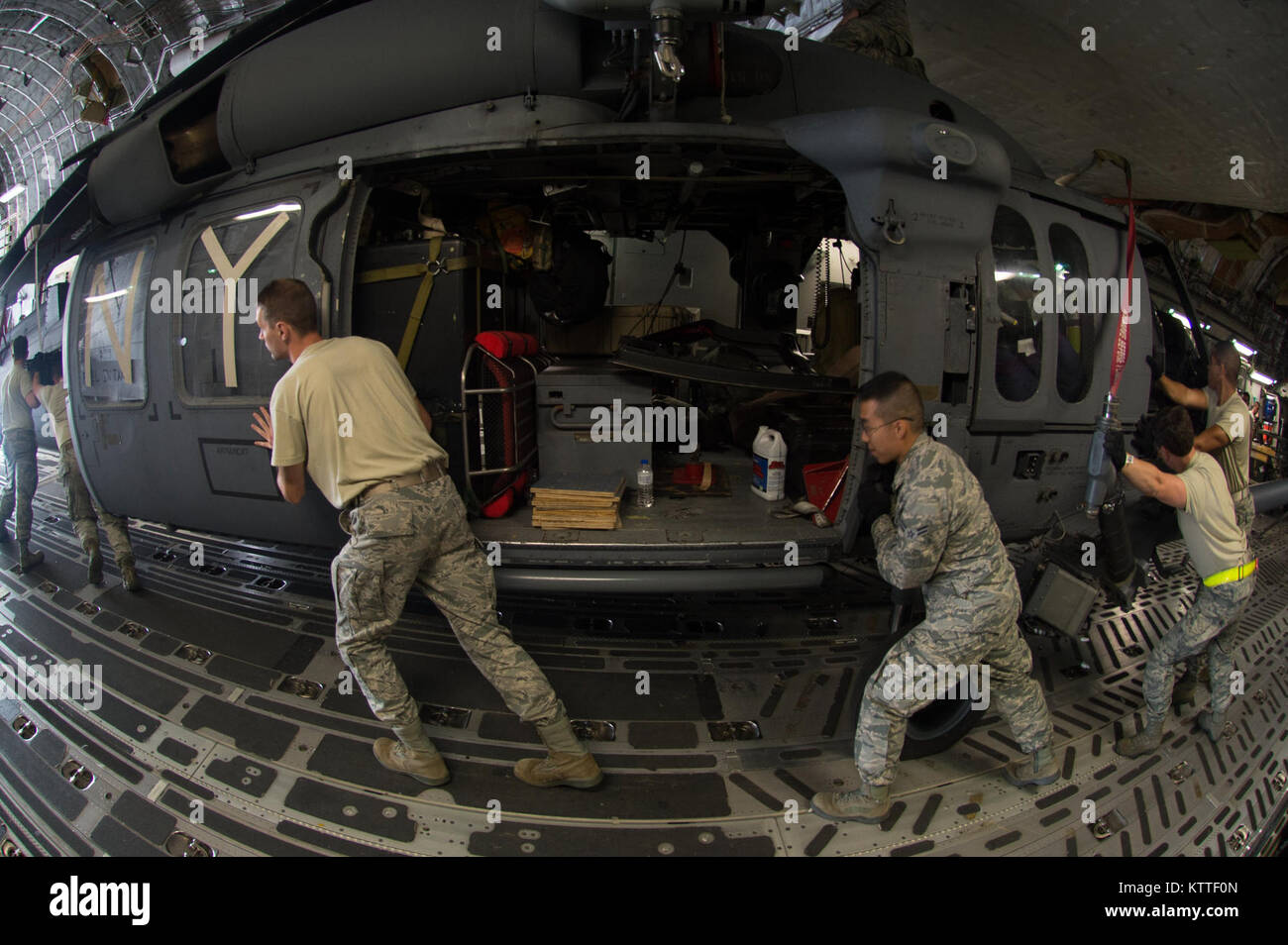 Airmen unload an HH-60 Pave Hawk helicopter from the back of a C-17 ...