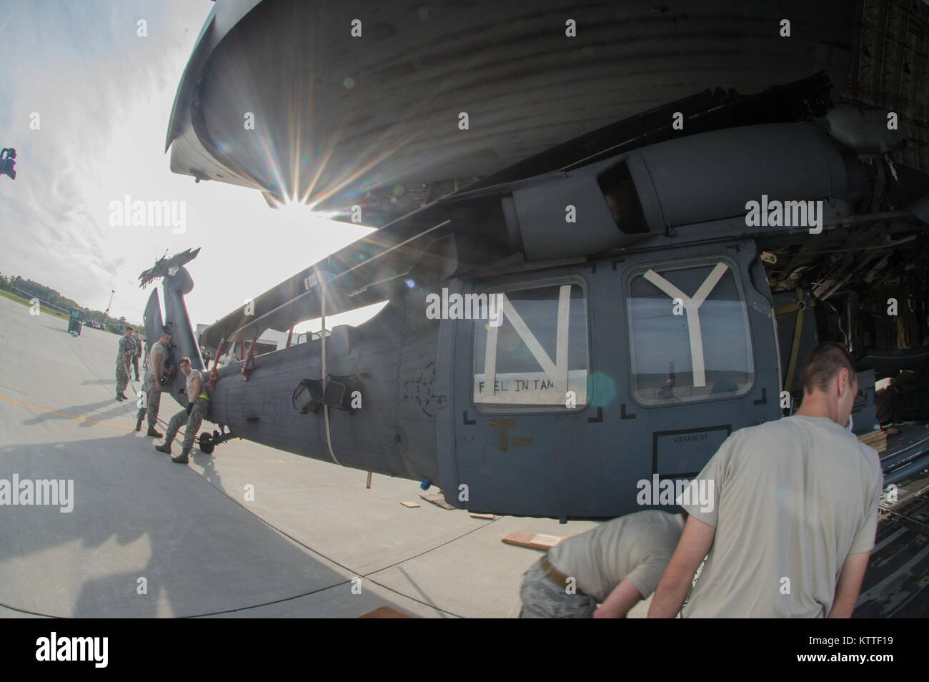Airmen unload an HH-60 Pave Hawk helicopter from the back of a C-17 ...