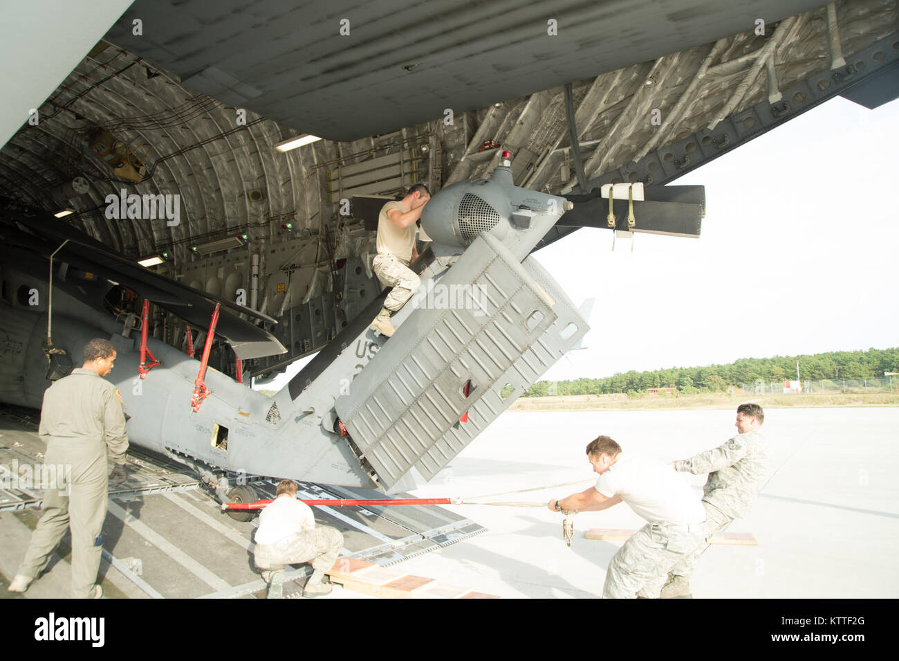 Airmen unload an HH-60 Pave Hawk helicopter from the back of a C-17 ...
