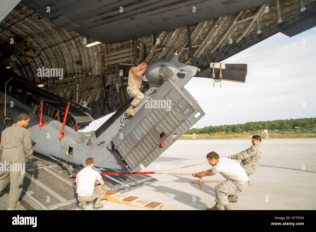 Airmen unload an HH-60 Pave Hawk helicopter from the back of a C-17 ...