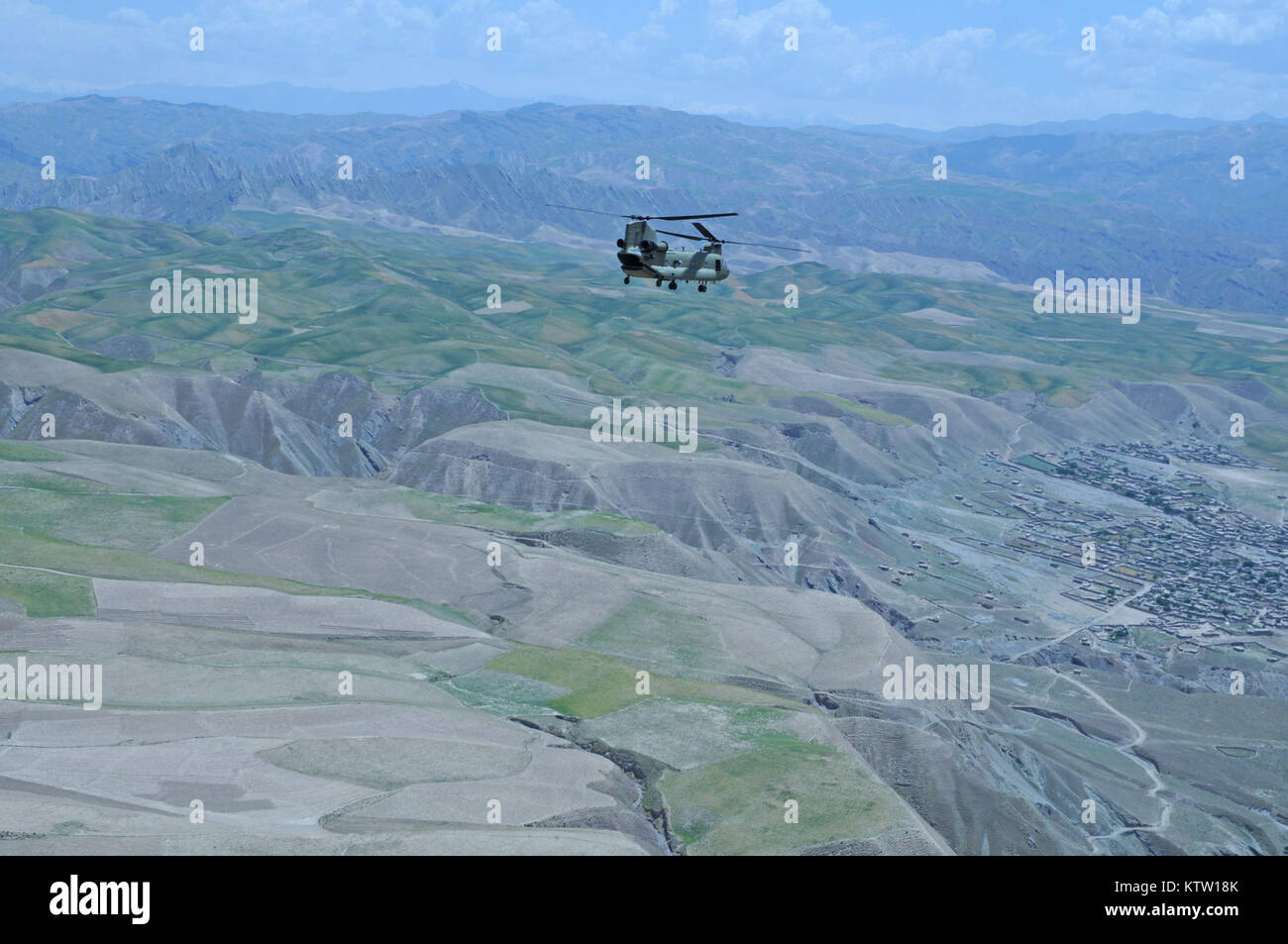 An aerial view of a Chinook helicopter flying over the mountains ...
