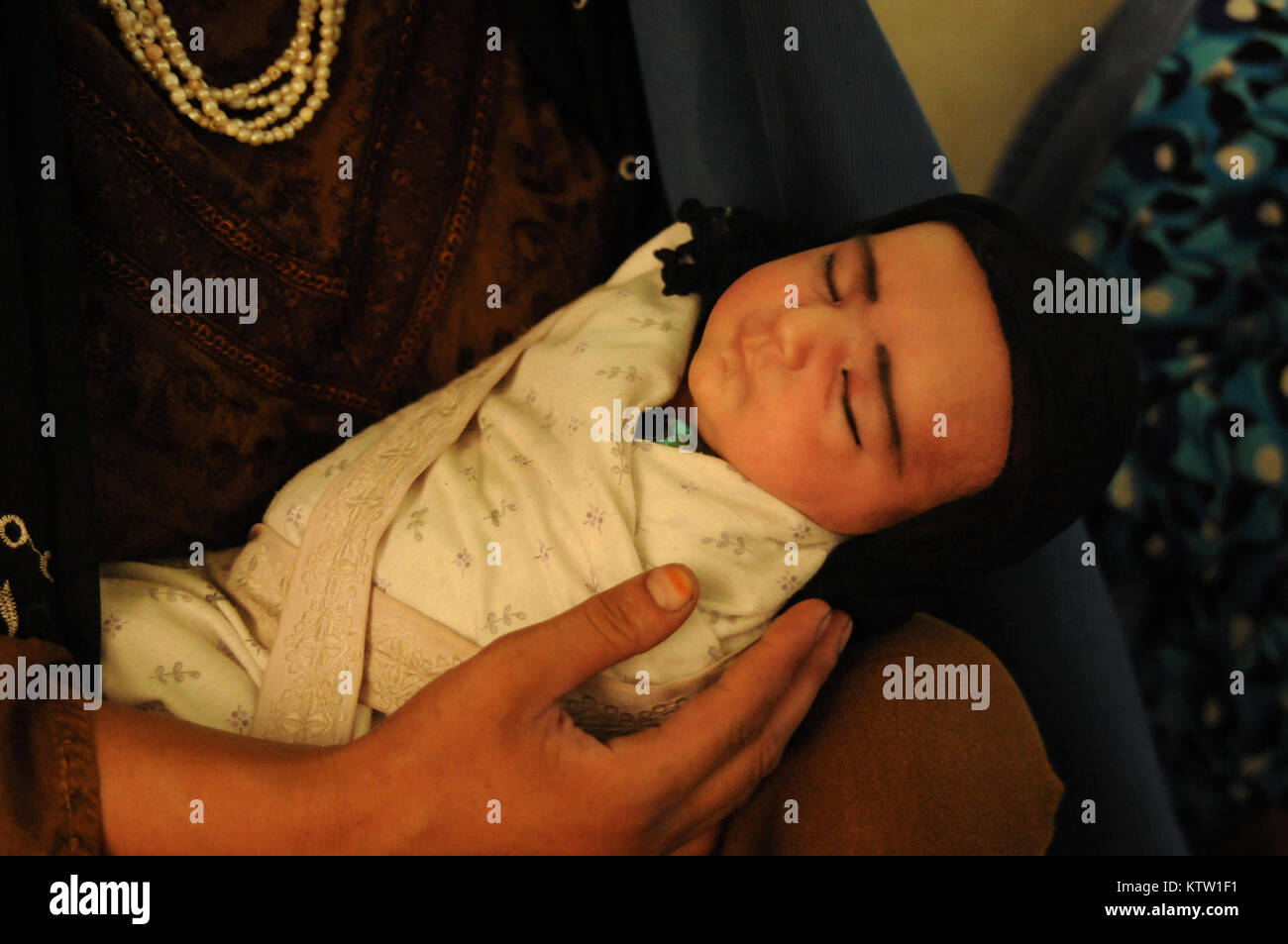 An Afghan mother holds her baby and waits to be seen at the medical ...