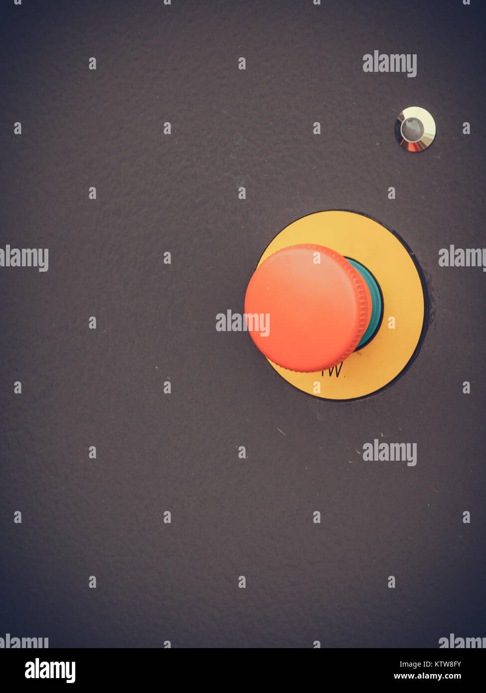 Yellow red emergency button on black machine and little silver screw ...