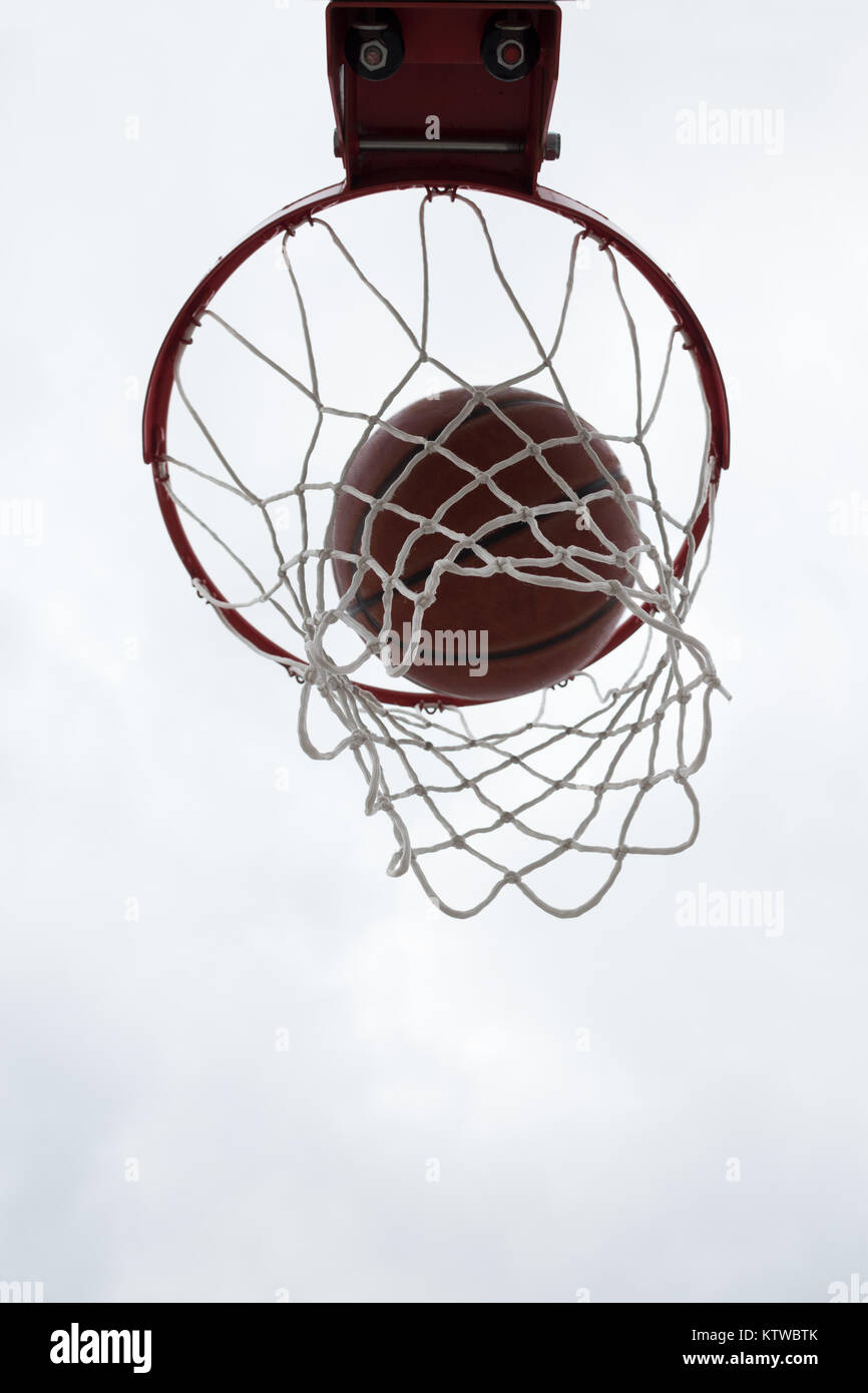Ball inside red basketball hoop, basket against white sky. Outdoor ...