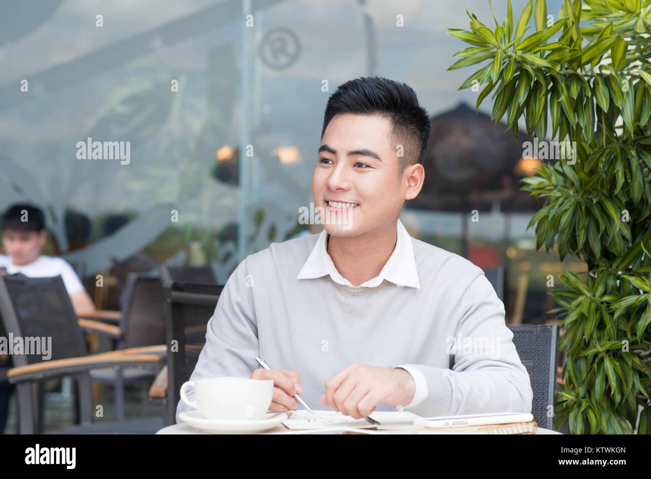 Happy young man working on laptop computer during coffee break in cafe ...
