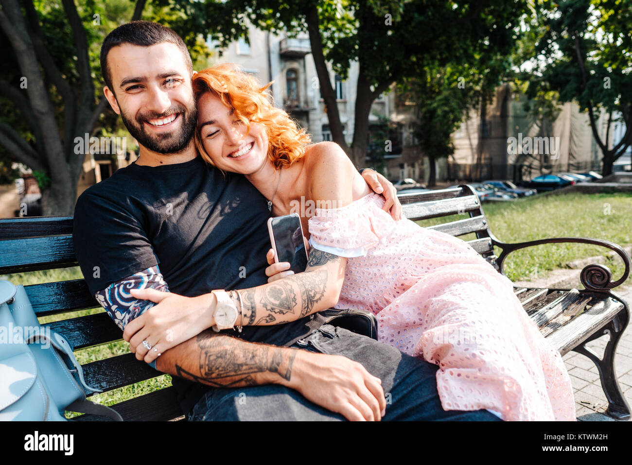 Beautiful dating couple hugging on a bench Stock Photo - Alamy