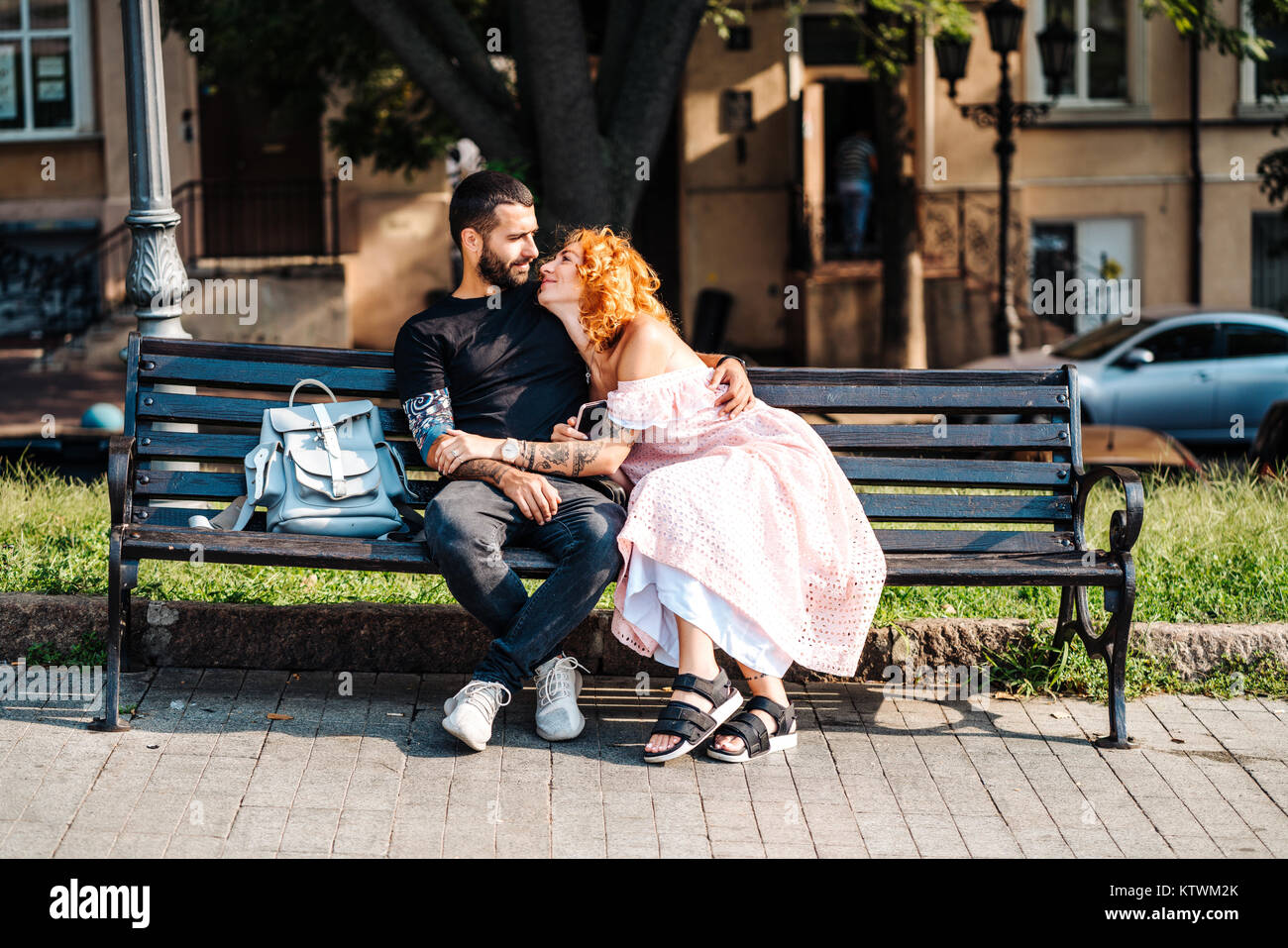 Beautiful dating couple hugging on a bench Stock Photo - Alamy