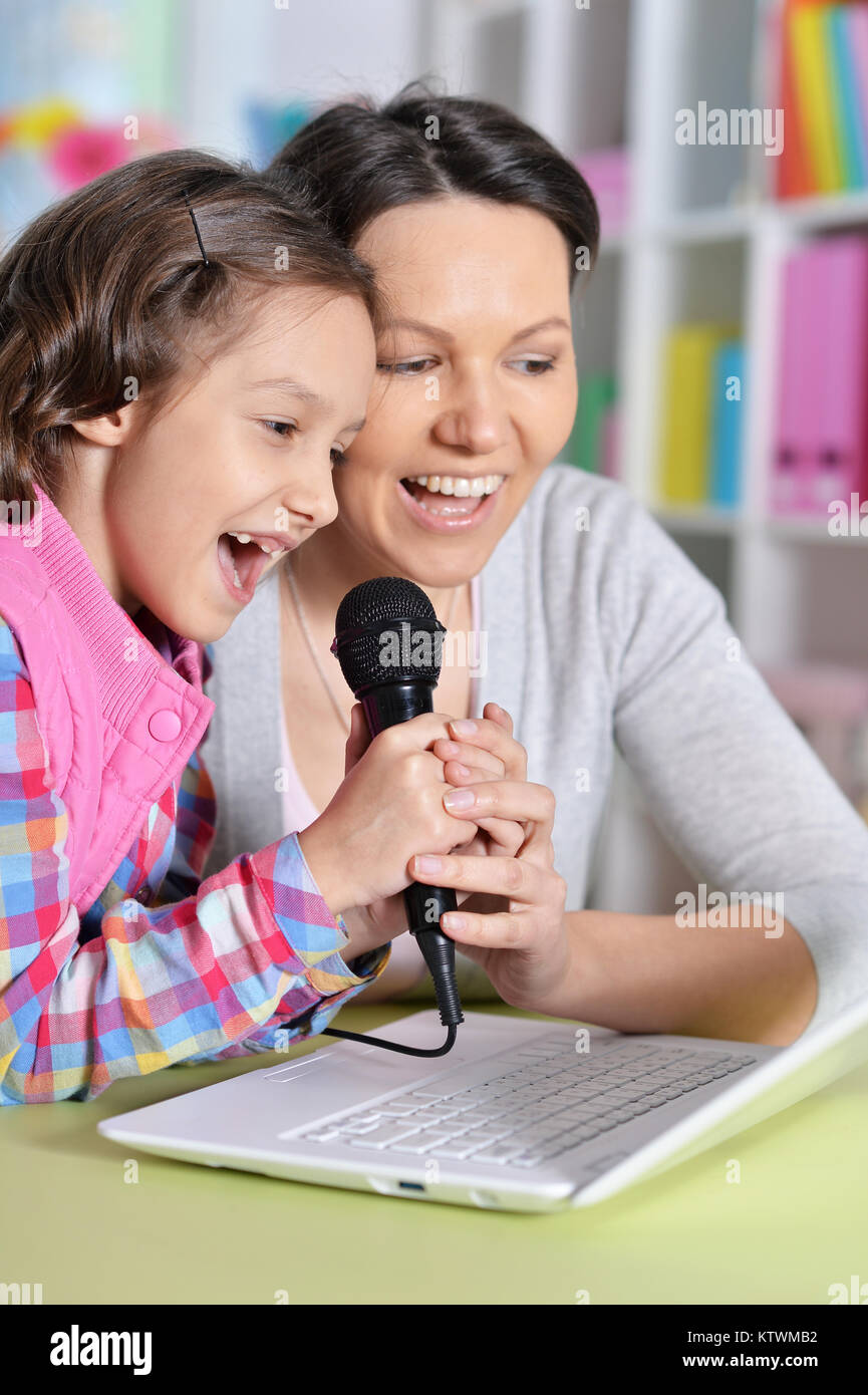 girl sitting at table and singing karaoke with mother Stock Photo - Alamy