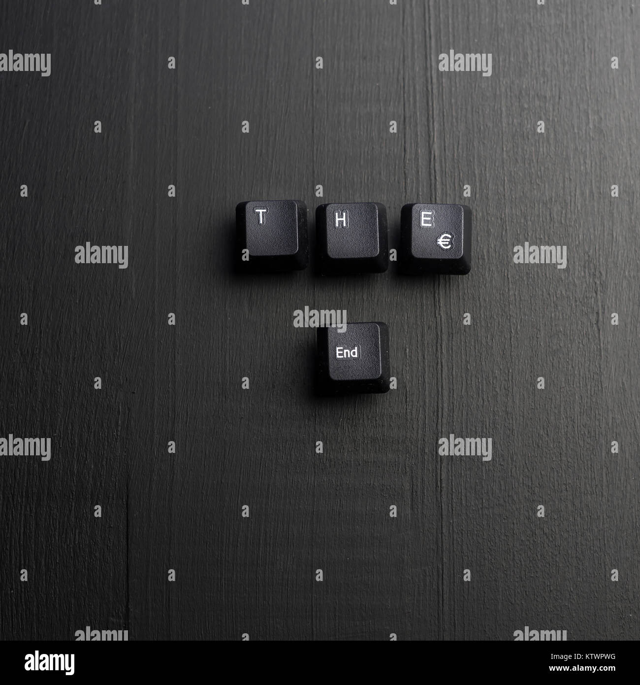 'The end' written with computer keyboard keys on a wooden background ...