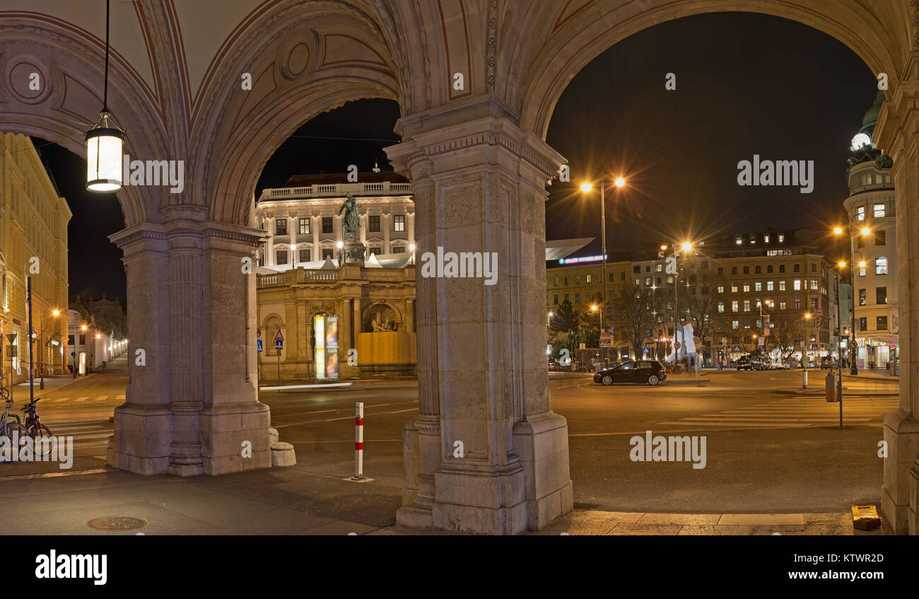 View of illuminated Albertina square at night through arches on pillars ...