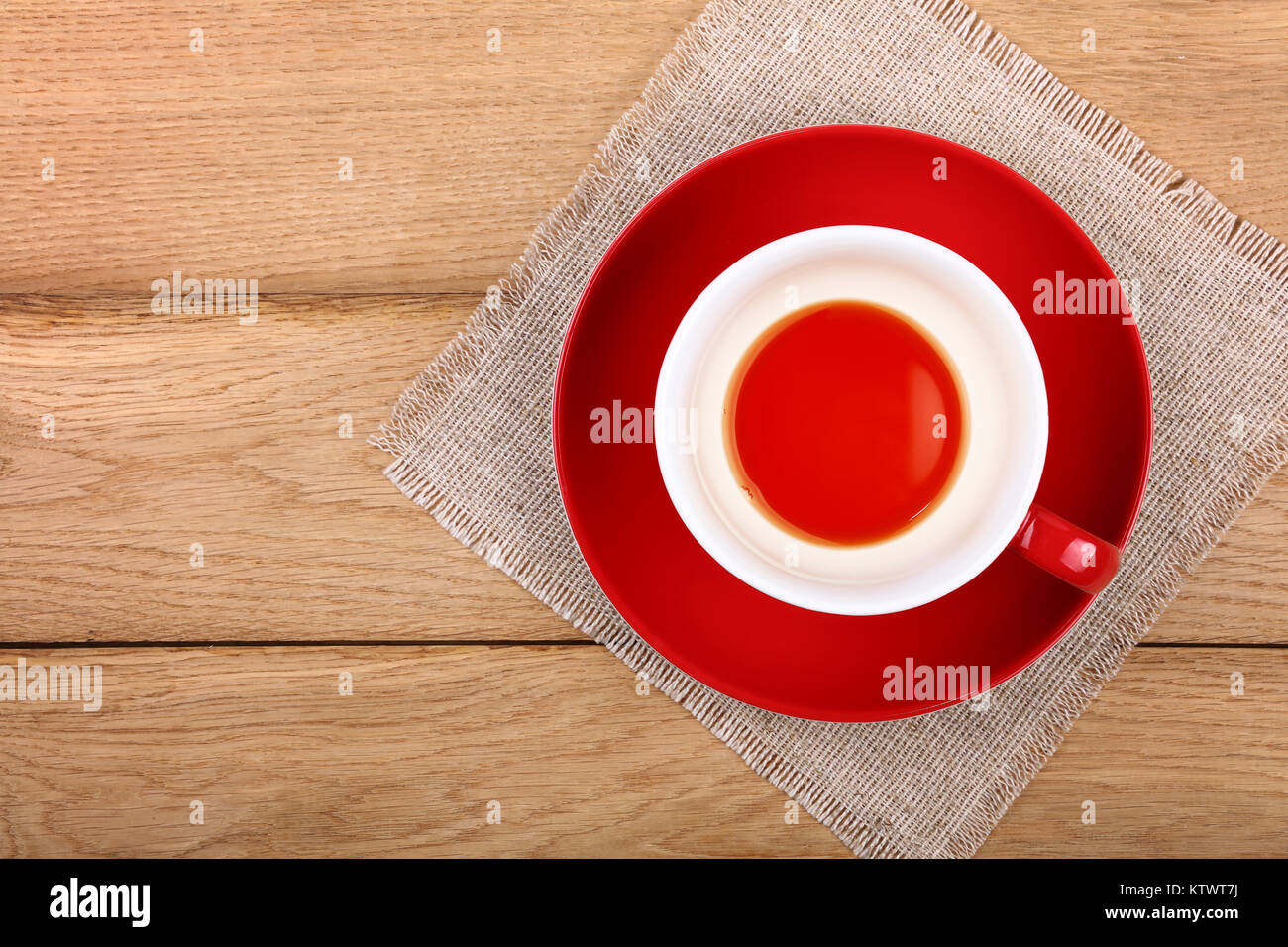 Empty finished cup of black tea on red porcelain saucer over wooden ...