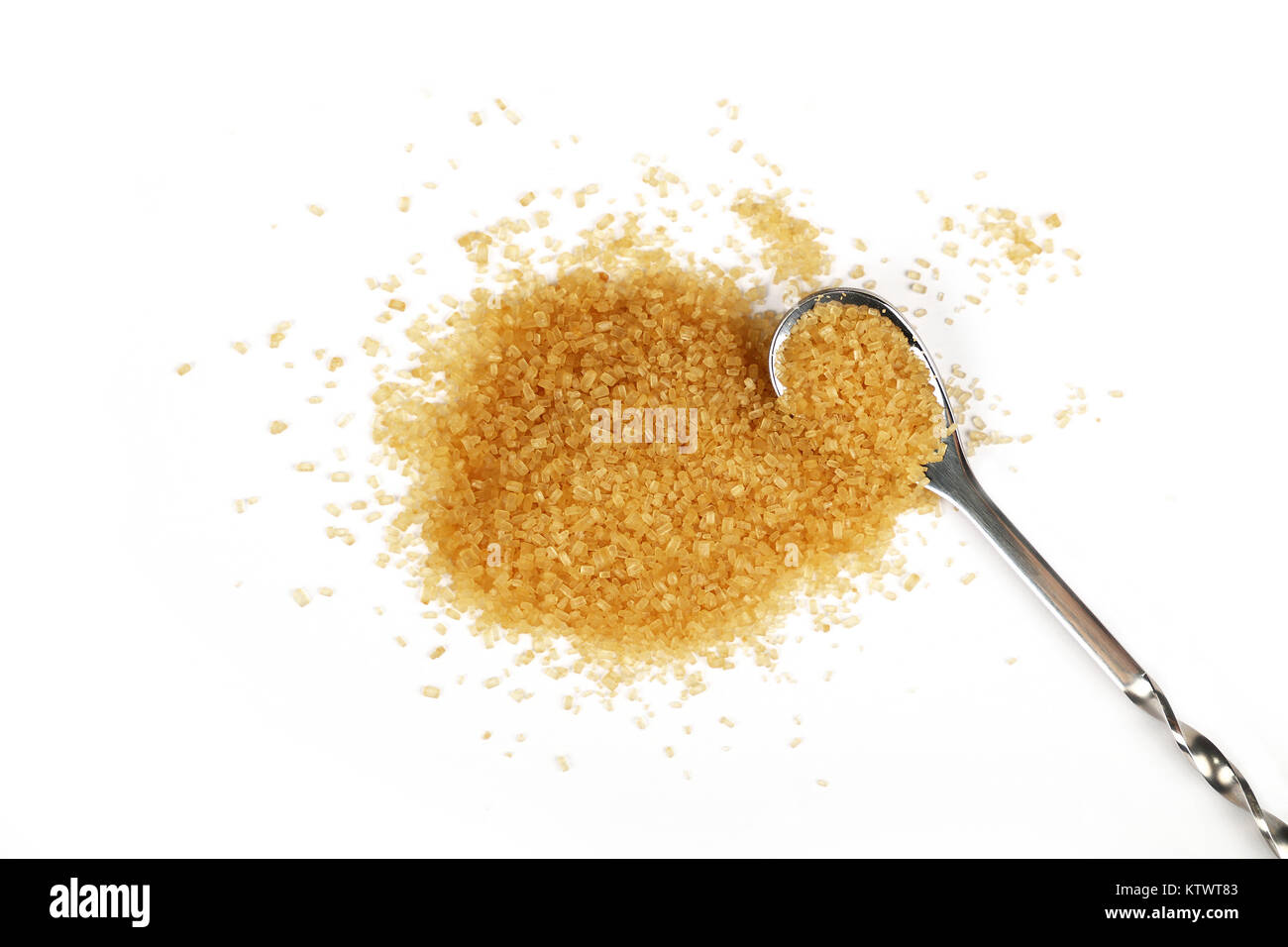 Metal spoon full of brown cane sugar with pinch of sugar spilled around ...