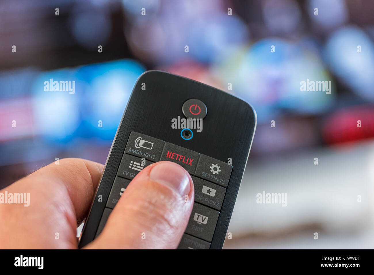 Man holds a remote control and push a Netflix button. Netflix Inc. is ...