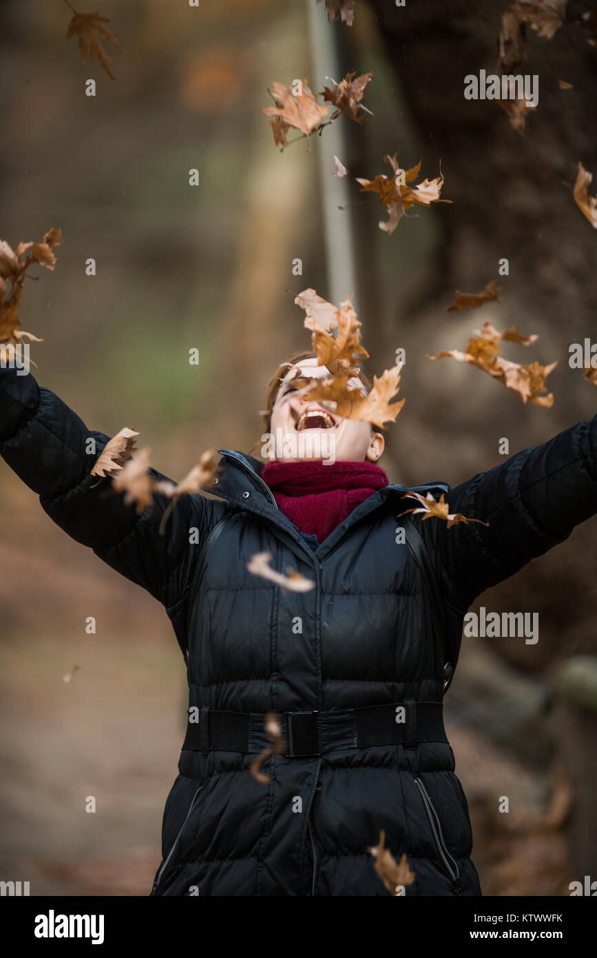 Woman throwing Leaves on the air, enjoying Life, Outdoor shots in Park ...