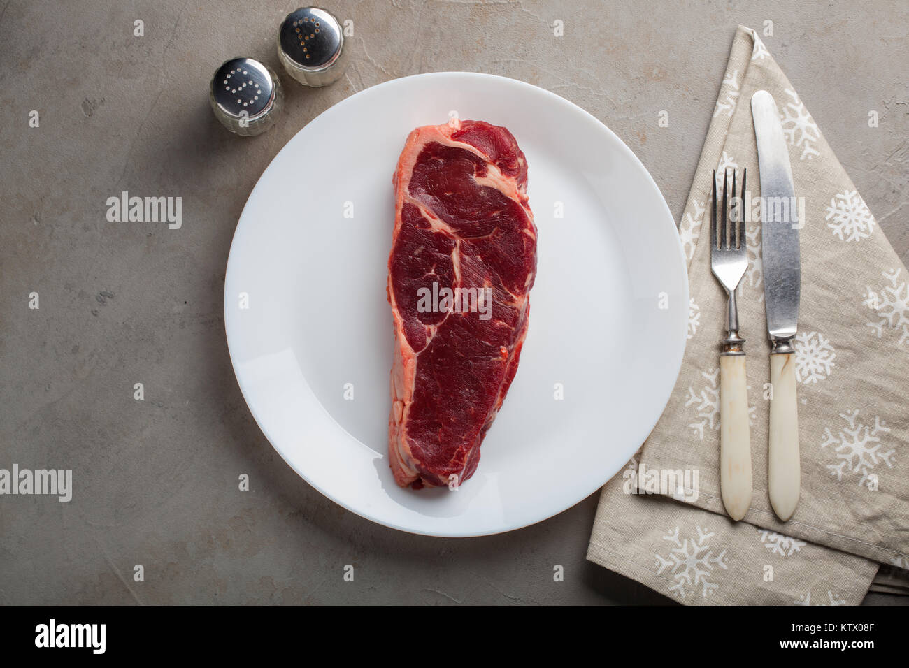 Raw beef marbled steak with vintage white utensils on old stone ...