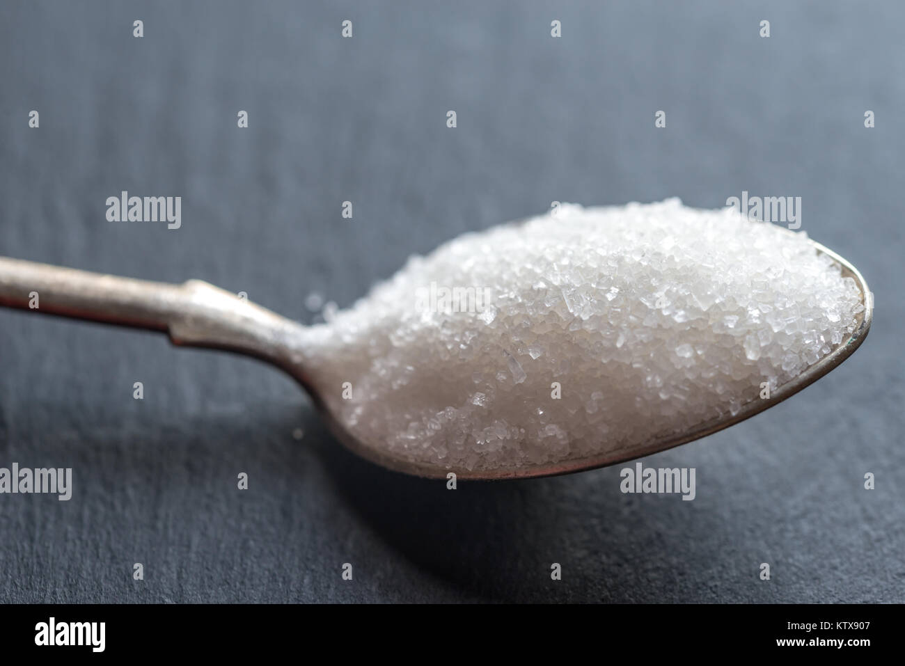 Spoon with white sugar on the dark background Stock Photo - Alamy