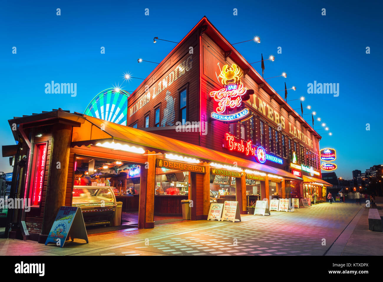 Neon lights illuminating street at night next to Miner's Landing, with ...