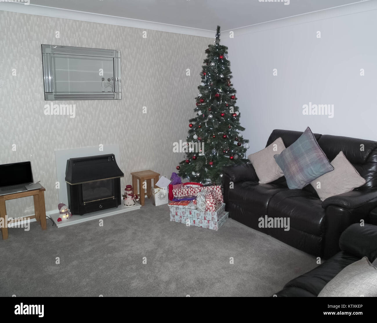 A Modern Lounge with Christmas Tree Decorated with presents at its base ...