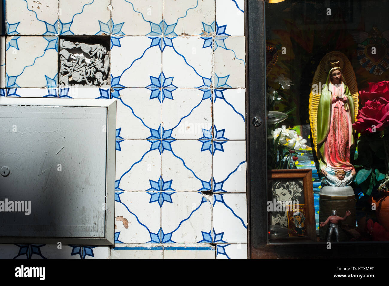 A strange shrine of kitsch items next to azulejo ceramic tiles with a ...