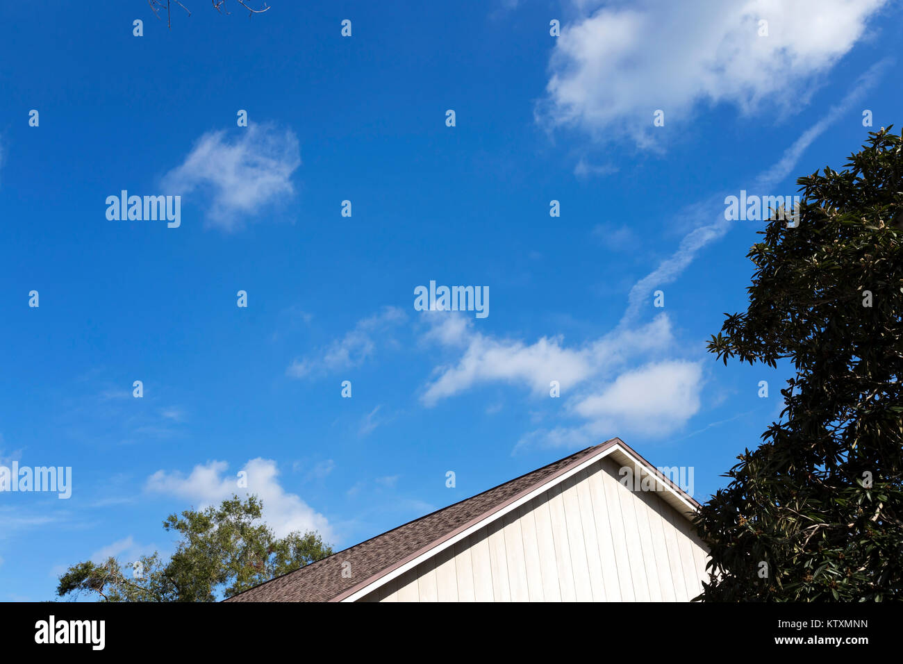 Vivid blue skies with clouds, tree, rooftop and shadows in bright ...