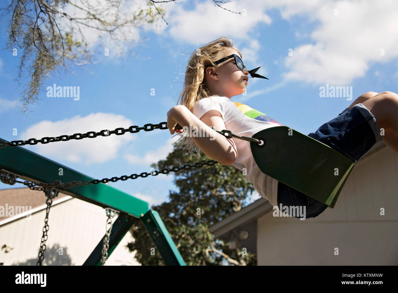 Young girl swinging on swing set outside on sunny day Stock Photo - Alamy