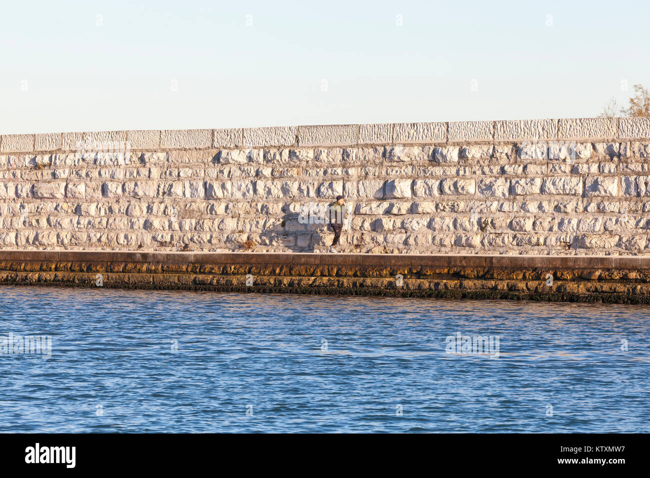Man jogging along the seawall around the Venetian Lagoon near Chioggia ...