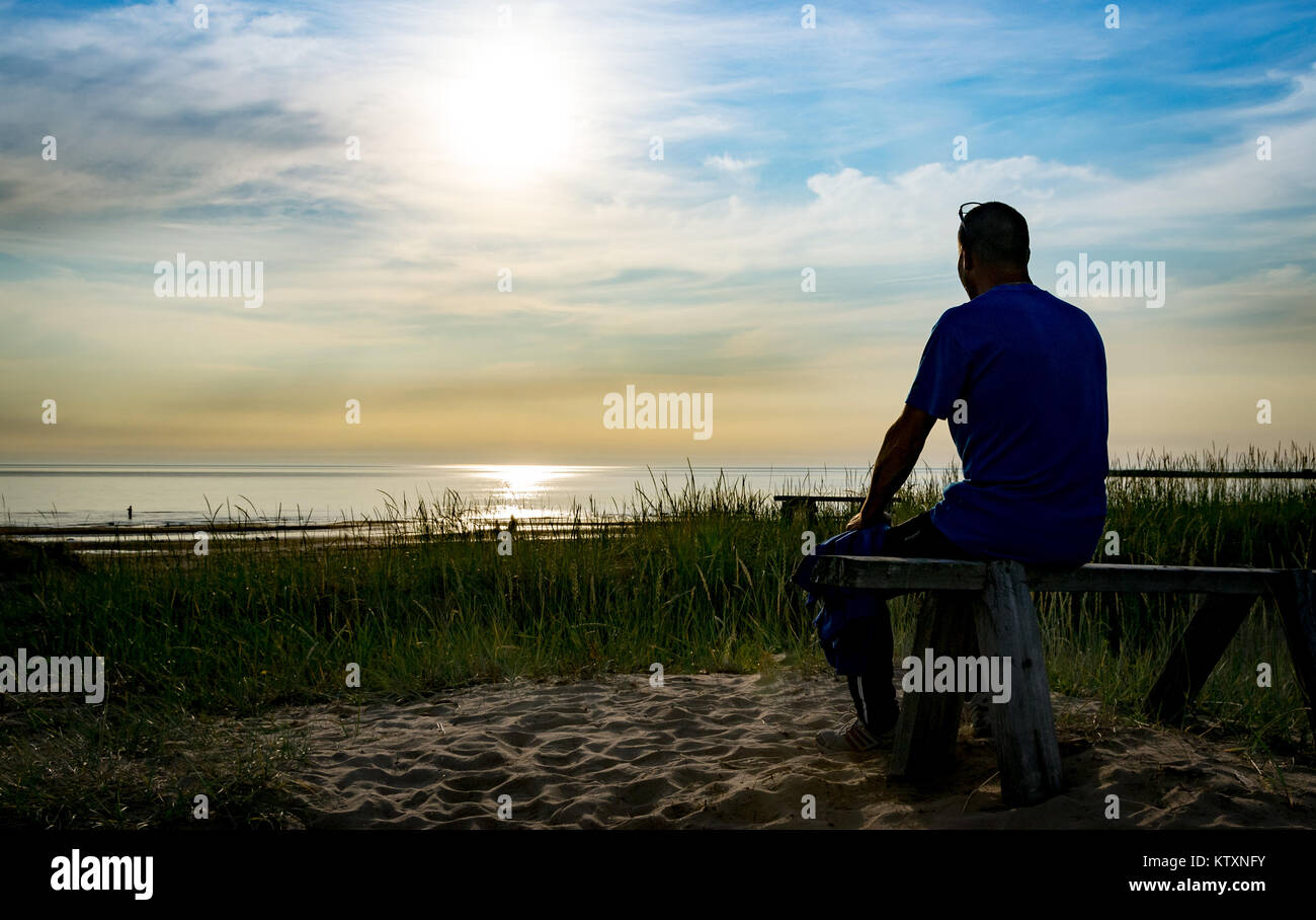 Man sitting and watching the sunset Stock Photo - Alamy