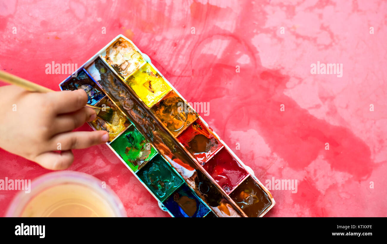 Child's hand picking color with brush from watercolor set Stock Photo ...