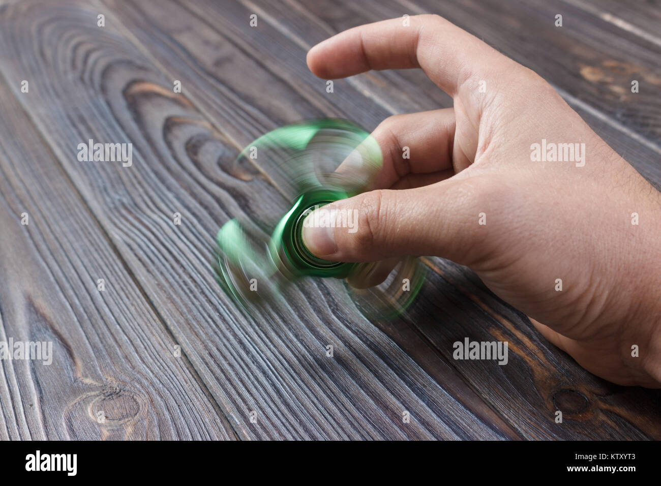 green hand spinner, or fidgeting spinner, rotating on man's hand Stock ...