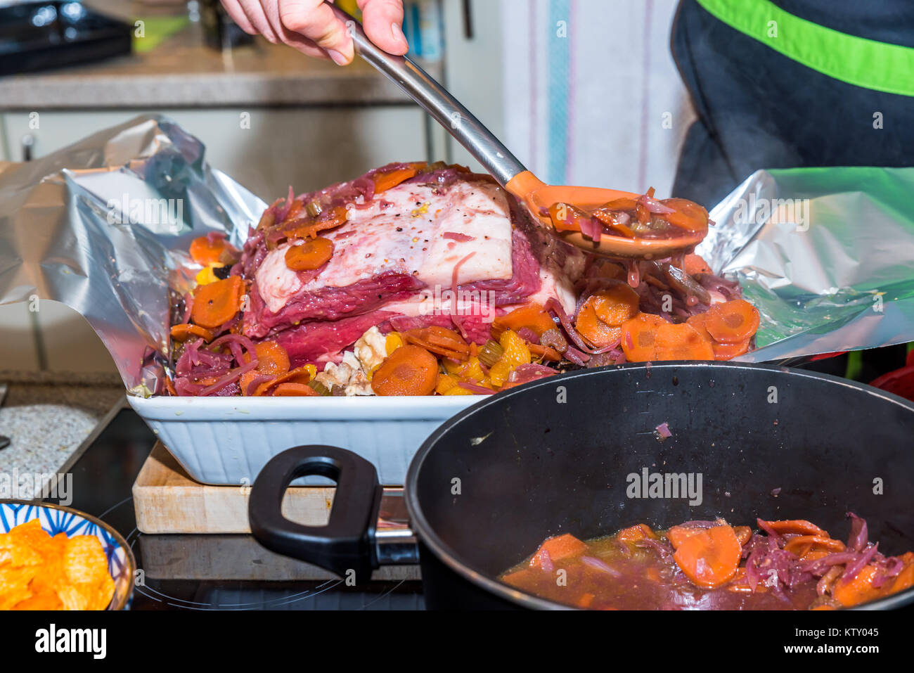 Male hand spraying cooked vegetables with sauce over raw beef rib steak ...