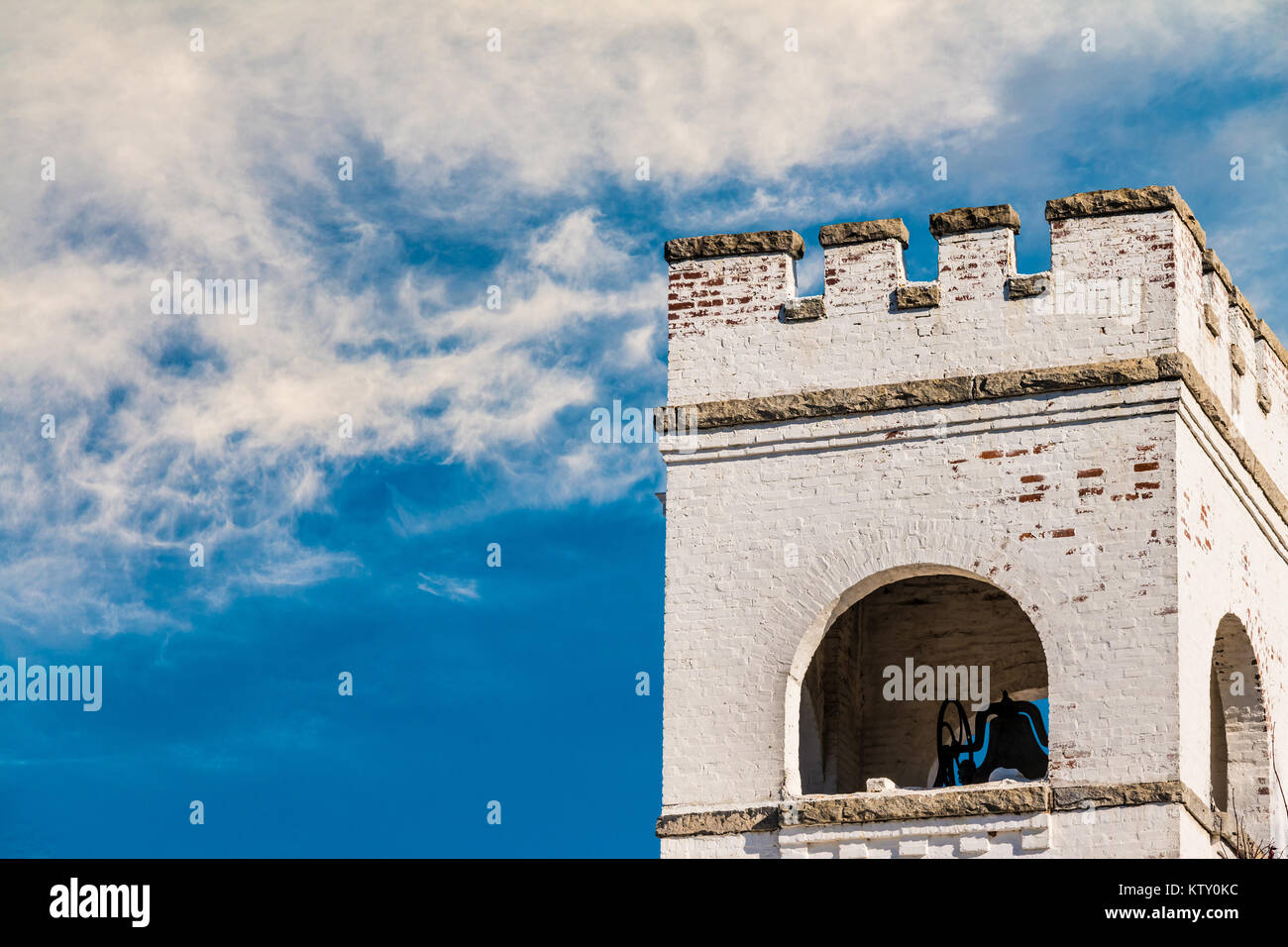 Low angle view of the white brick bell tower on the background of ...
