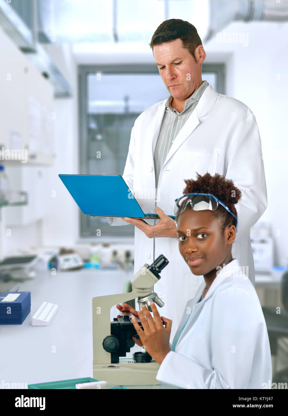 Scientists, senior Caucasian male and young African female, work in ...