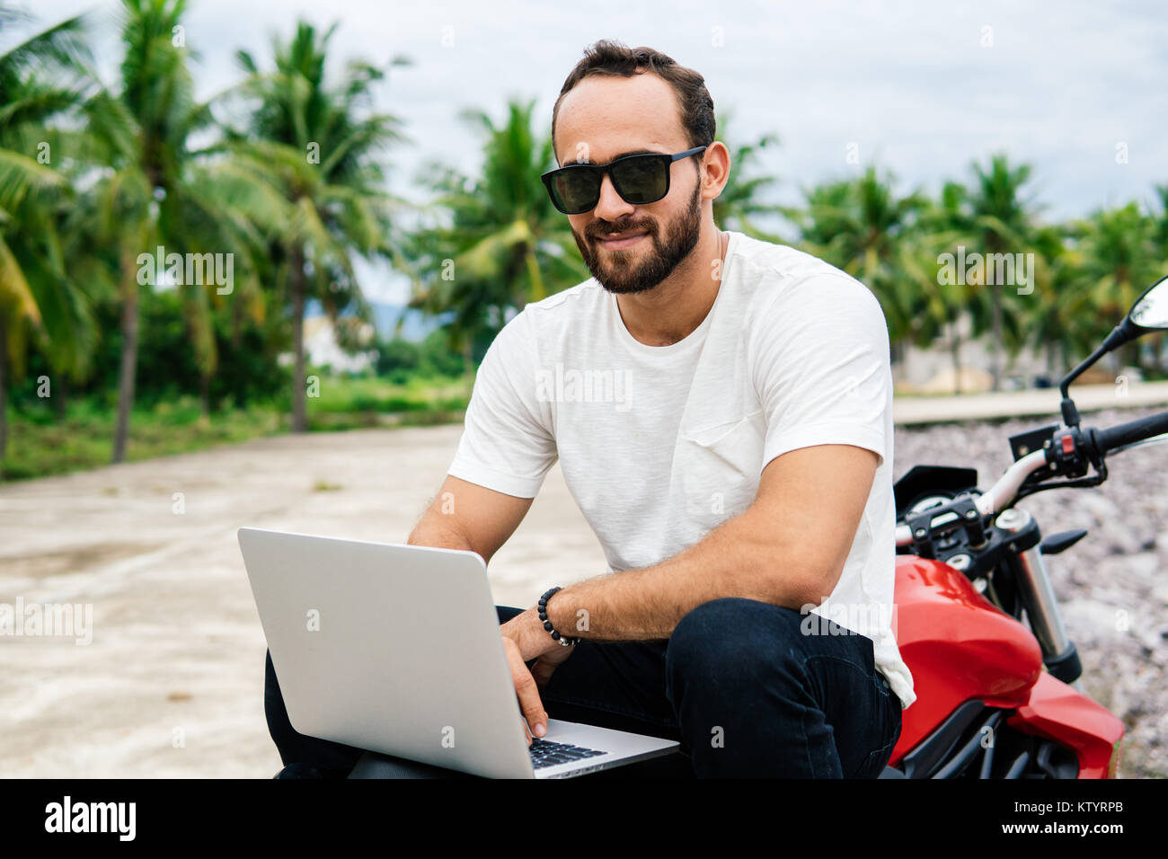 Man working on laptop computer while sitting on his motorbike Stock ...